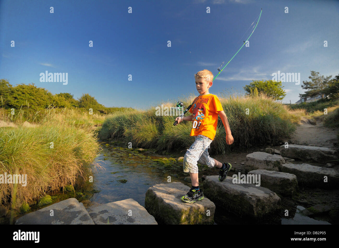 young boy fishing crossing stepping stones river teifi estuary poppit ...