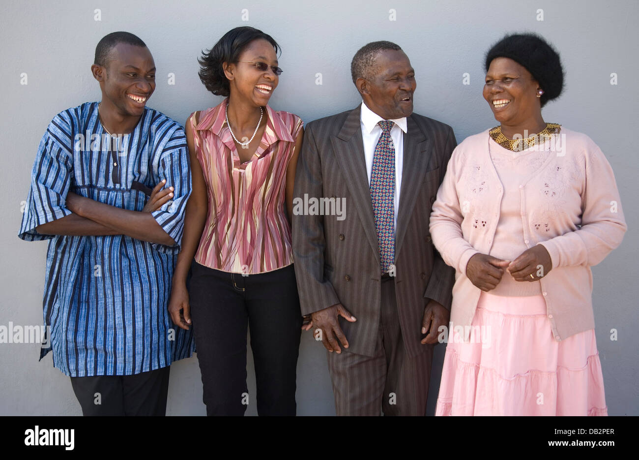 4 African people standing together against a wall with happy ...