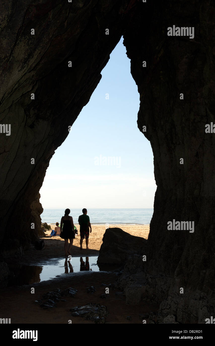 A couple arrive through arched cave at Pobbles Beach, Gower Peninsula ...