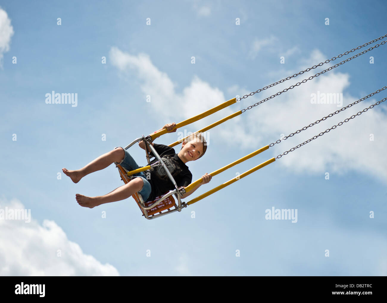 Young boy riding a swinging carousel Stock Photo - Alamy