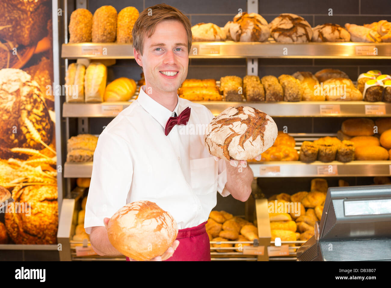 Shopkeeper in bakery presenting loafs of bread Stock Photo - Alamy