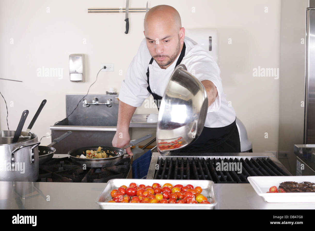 Chef in kitchen cooking, he is working on the sauce for the food Stock ...
