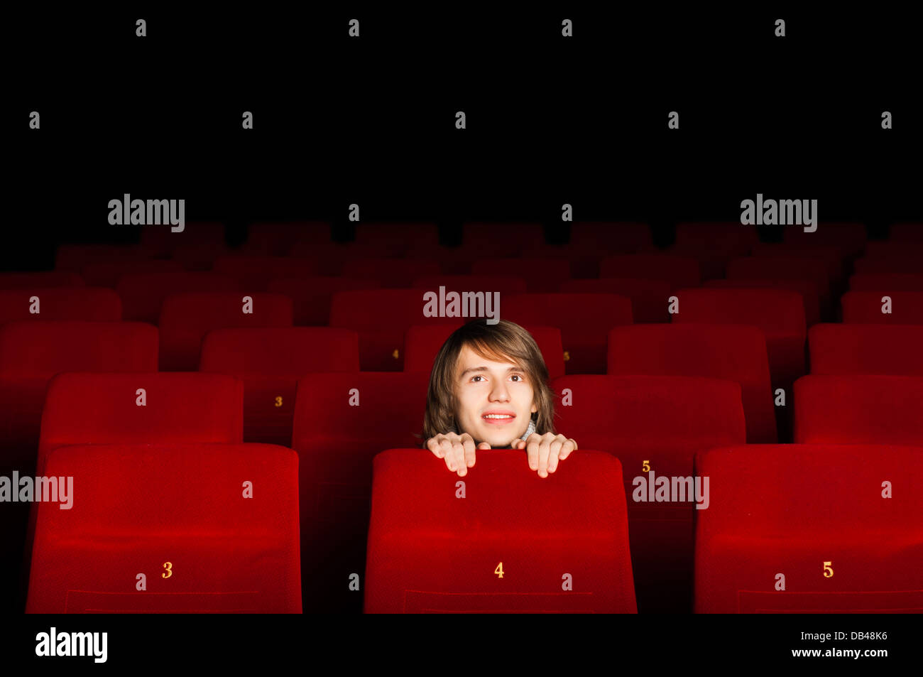 young man in the cinema hiding behind a chair Stock Photo - Alamy