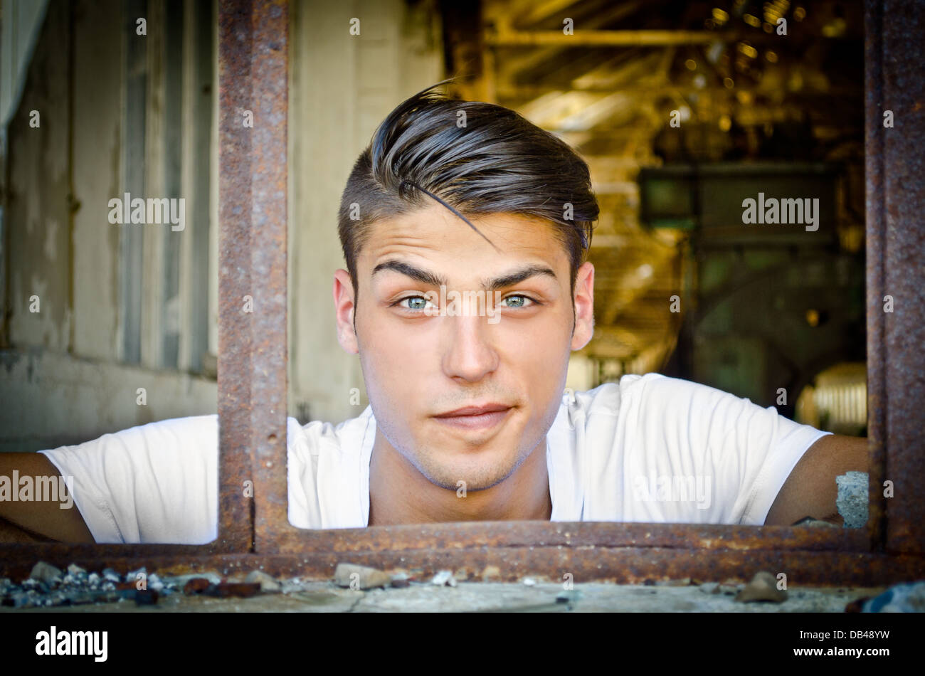 Attractive young man at rusty window with funny expression on his face ...