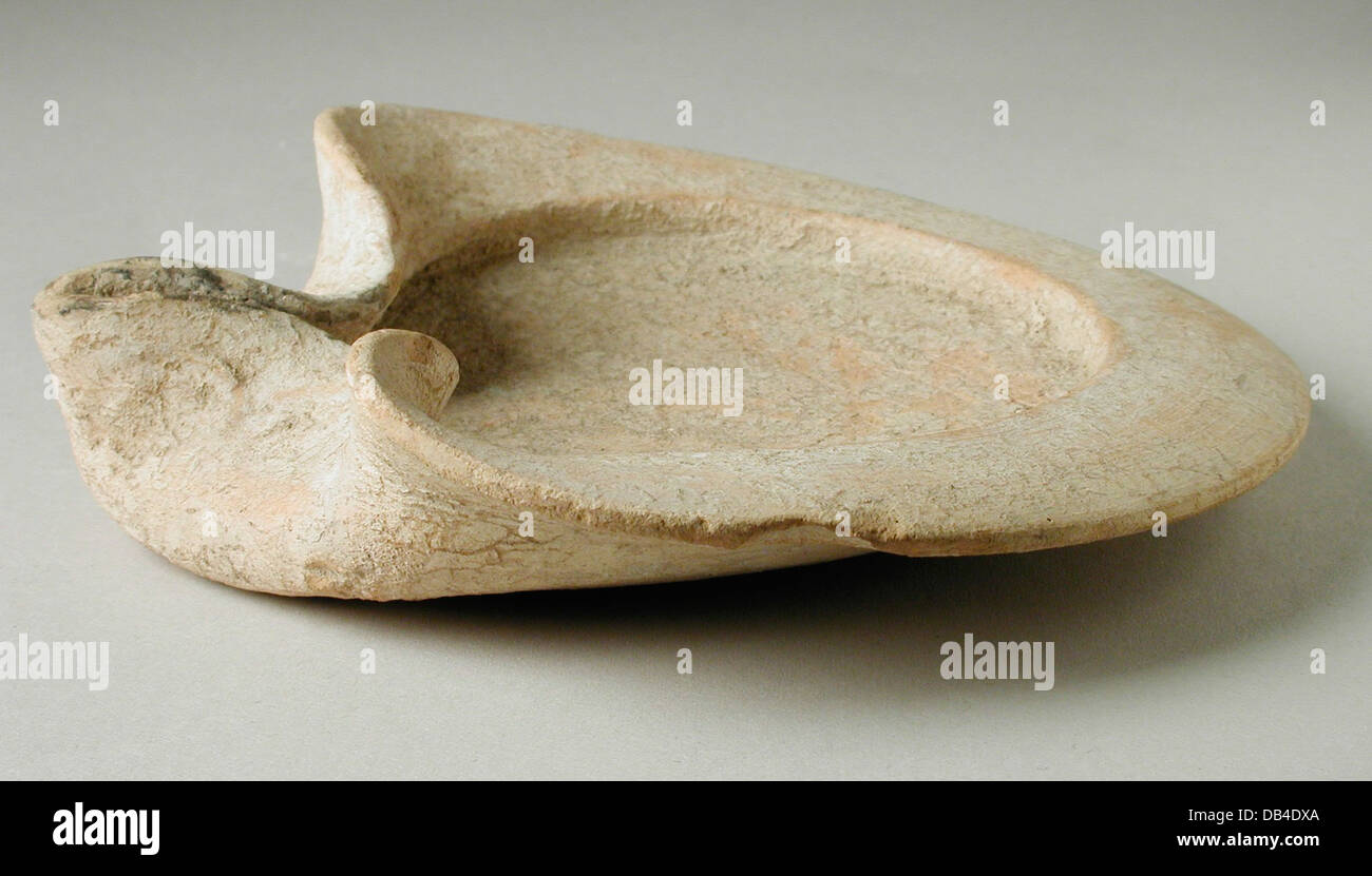 This oil lamp is a functional artifact from ancient times, showcasing ...