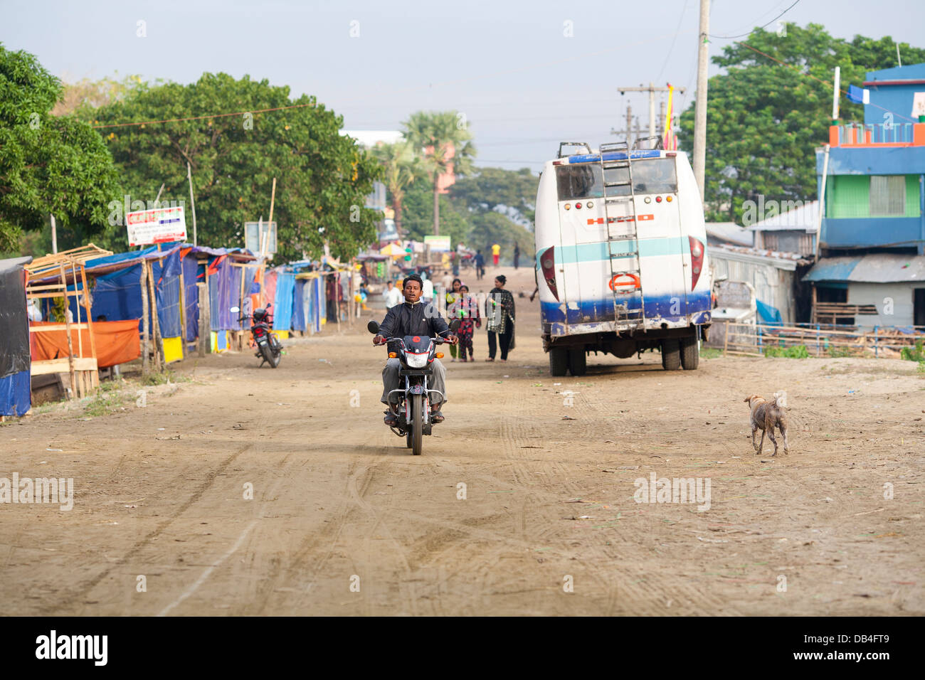 A motorbike passes a bus on the dusty main road of Kuakata beach in the ...