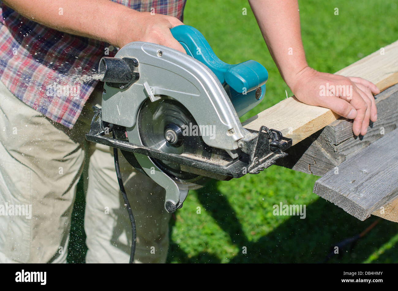Handyman using hand-held saw machine outdoors Stock Photo - Alamy
