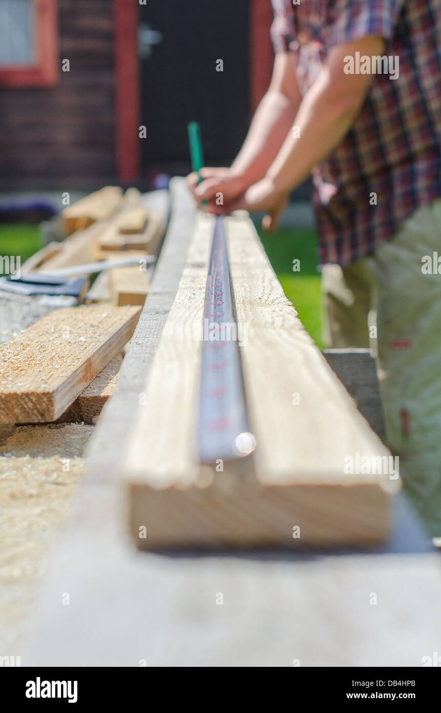 Male hands measuring and marking wooden plank outdoors Stock Photo - Alamy