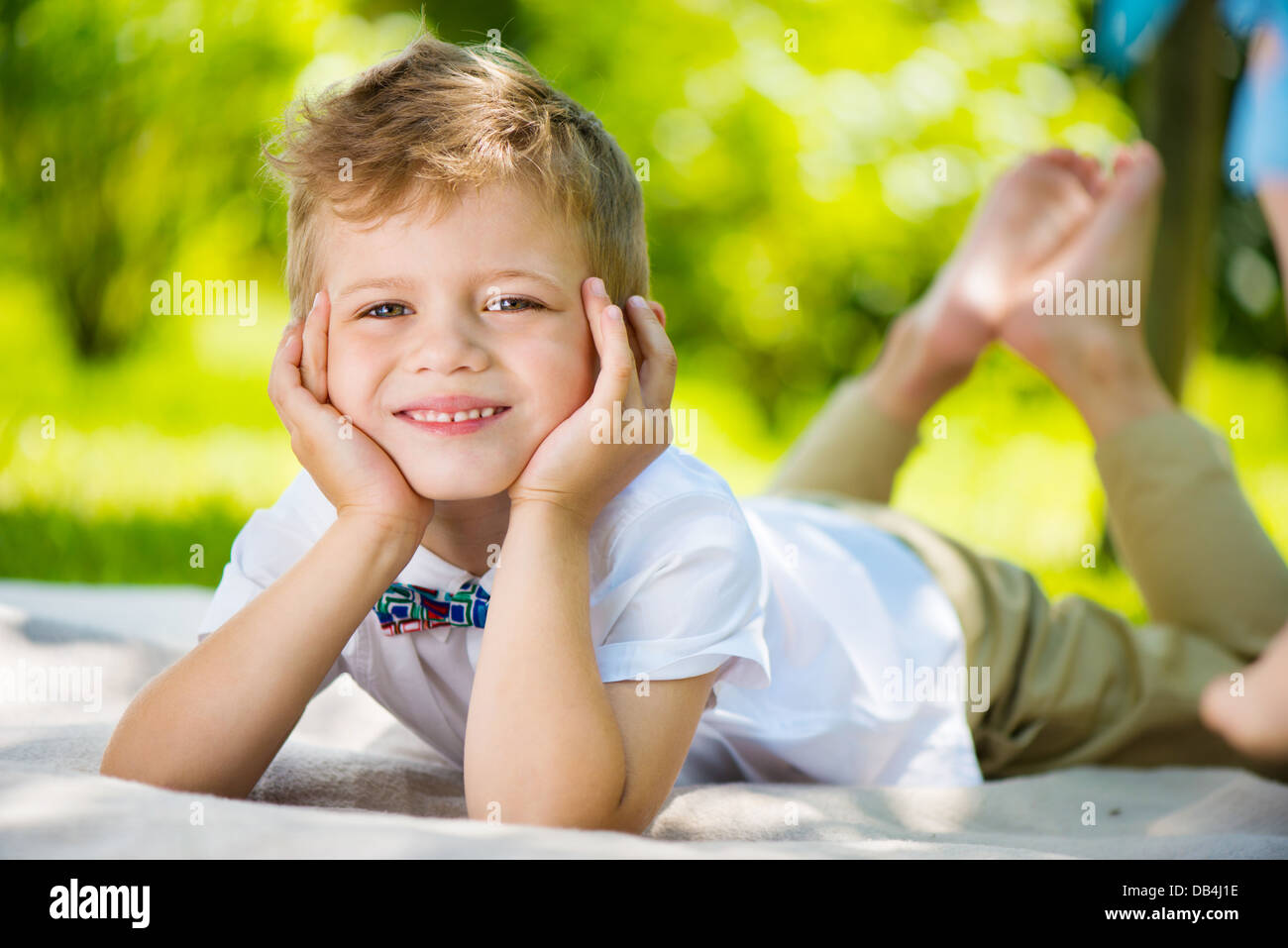 Cute little boy with butterfly lying on green grass at park Stock Photo ...