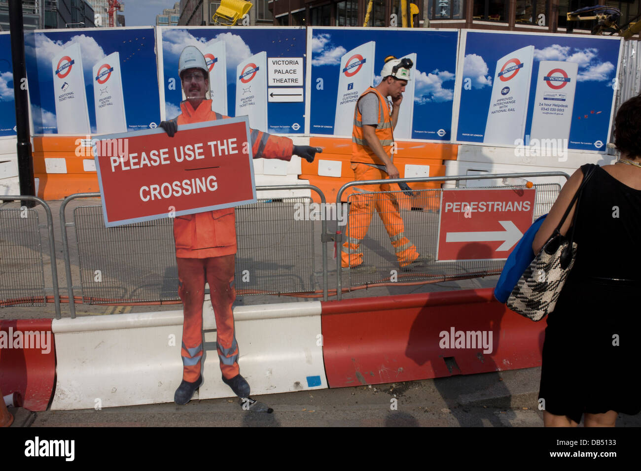 Construction worker and cut-out site character telling pedestrians ...