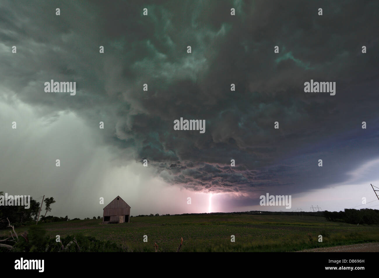 Lightning strikes a field beneath a squall line thunderstorm pouring ...