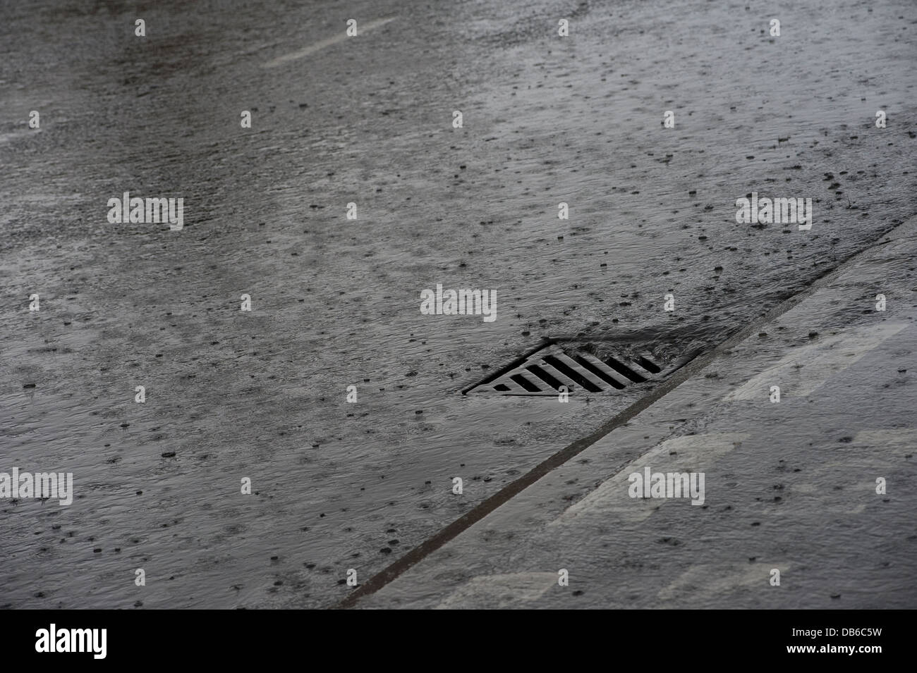 Road surface water draining into a drain during a downpour of rain on a ...