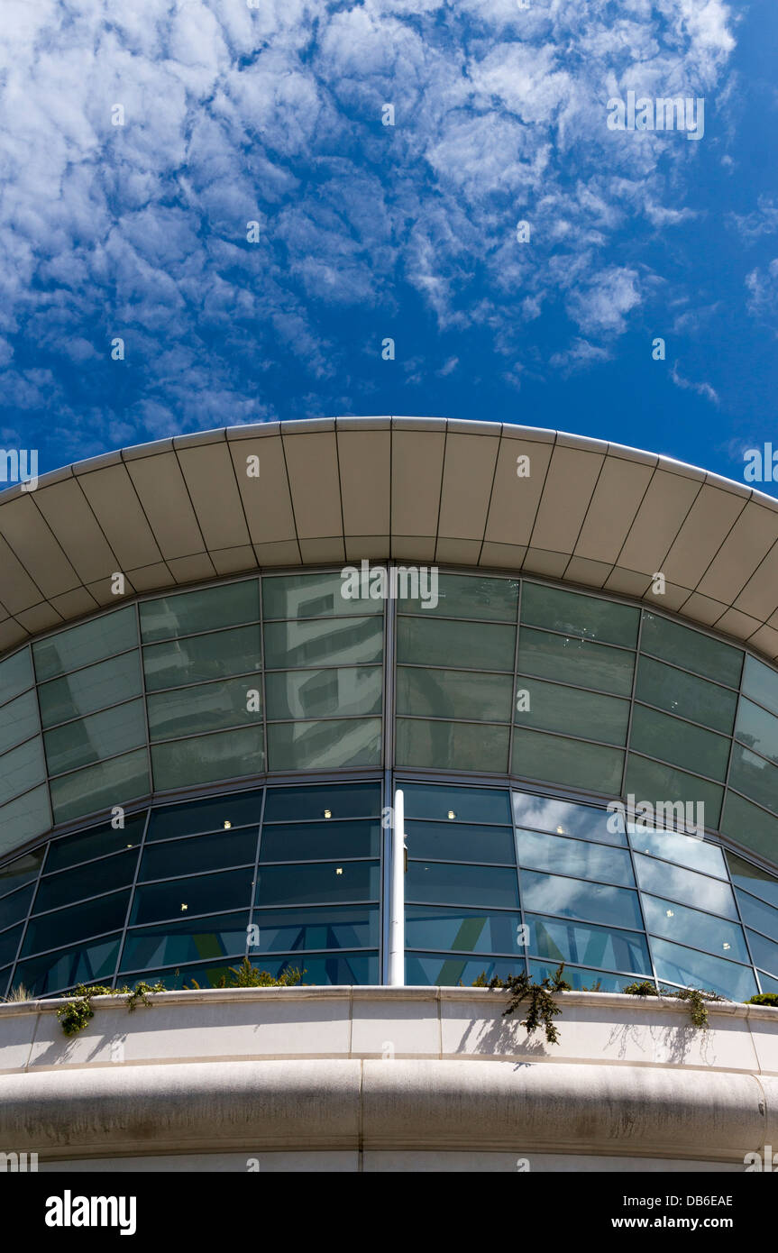 Looking up at curved roof line of modern building against blue sky UK ...