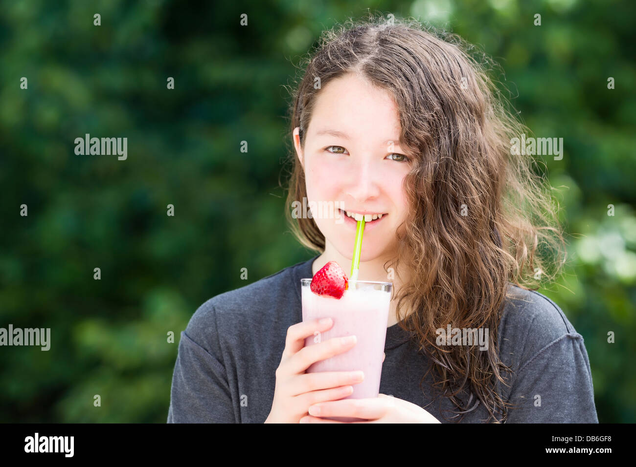 Photo of young girl smiling while sipping on a strawberry milkshake ...