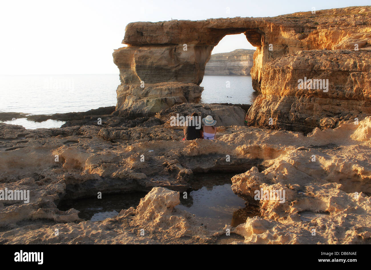 A couple siting and watching the natural arch high rock formation Azure ...