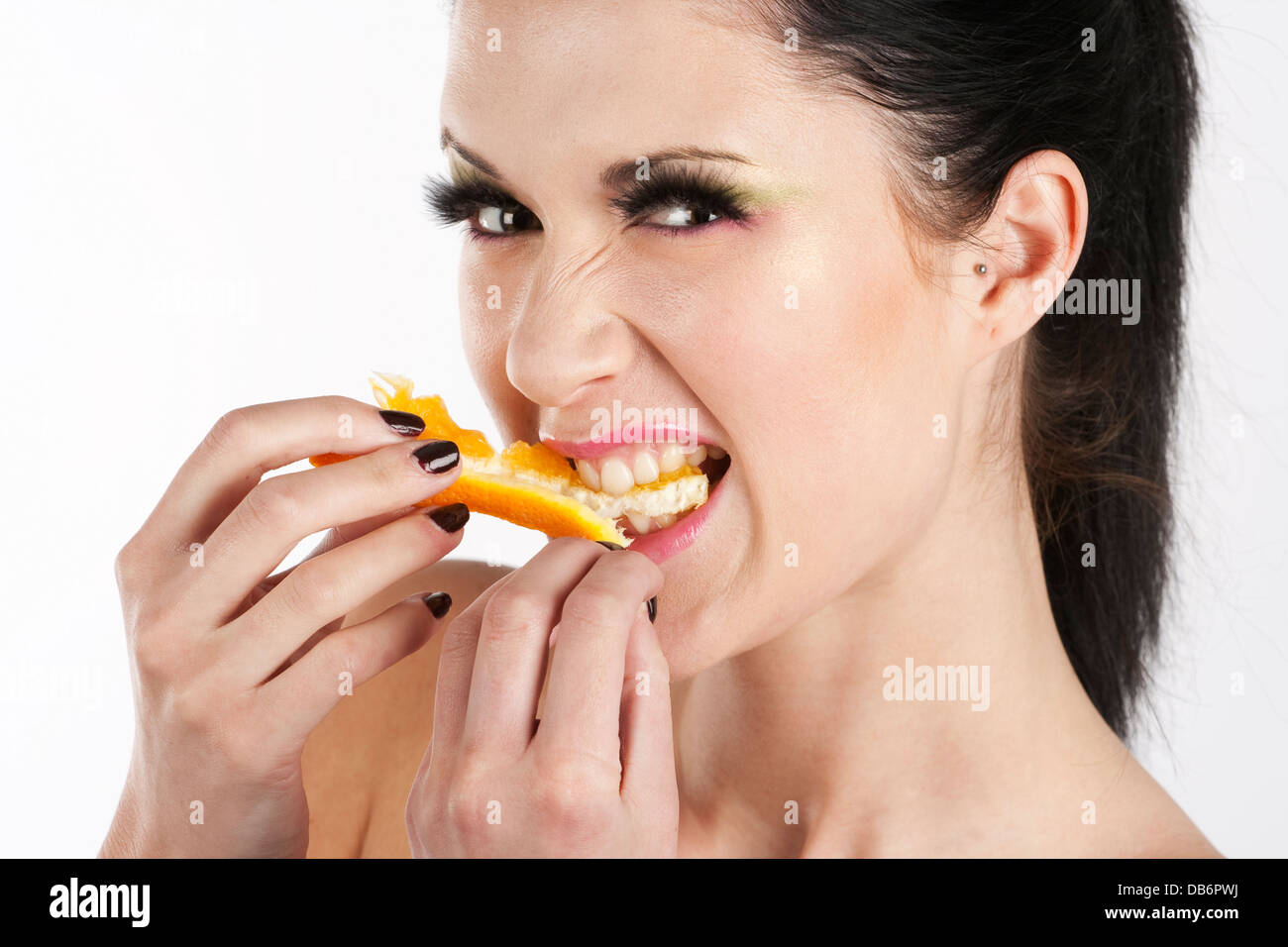 Beautiful women eating a slice of orange Stock Photo - Alamy