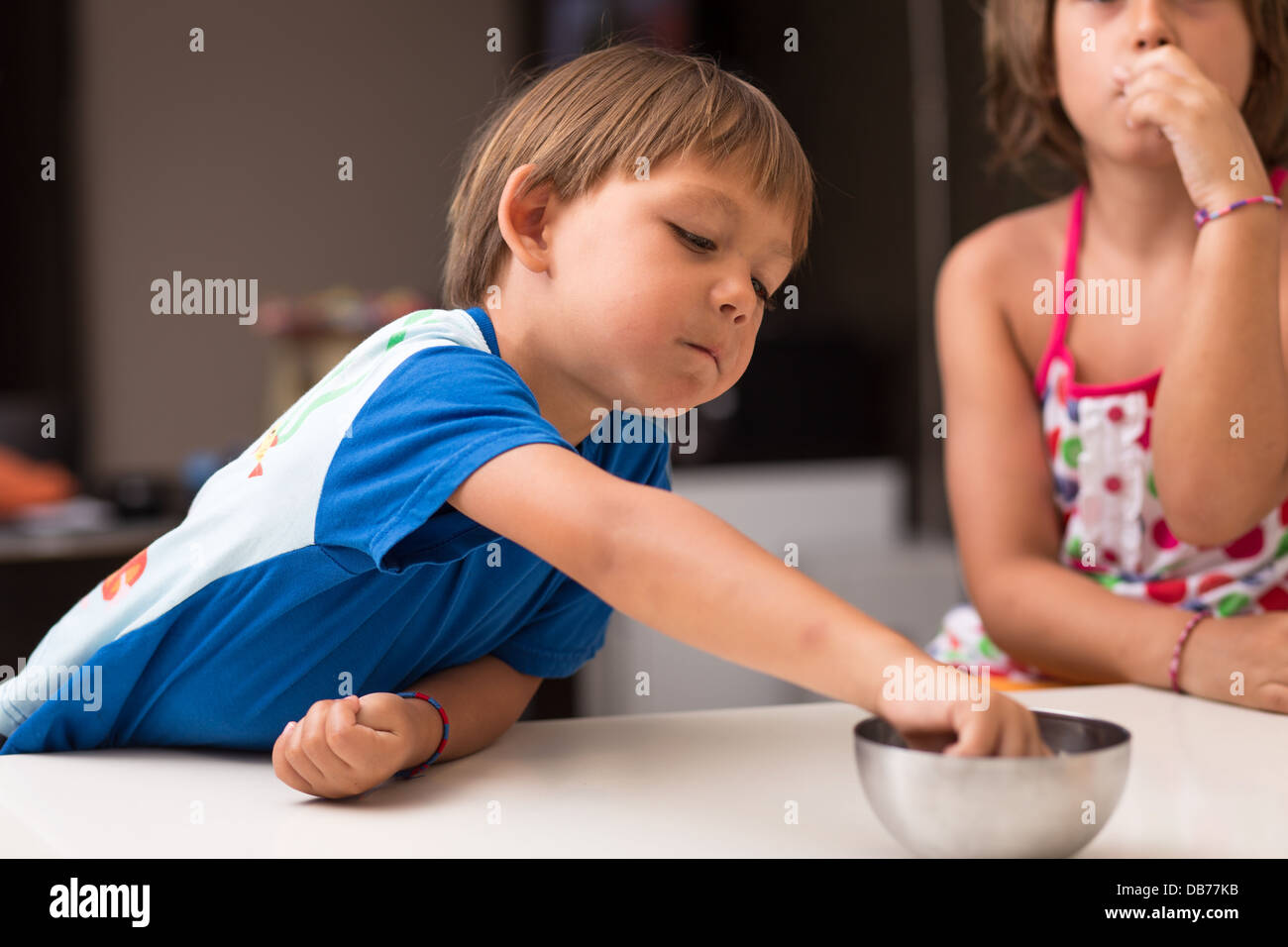 Little boy taking candy from a bowl in the kitchen Stock Photo - Alamy