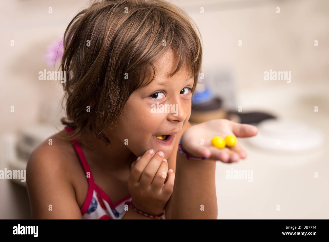 Young girl eating yellow chocolate candy Stock Photo - Alamy