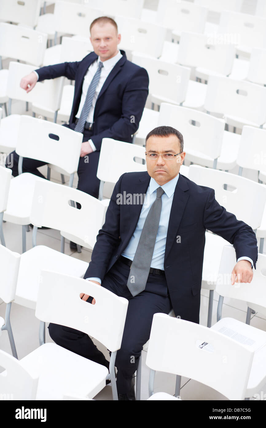 Confident businessmen sitting on chairs of conference hall Stock Photo ...