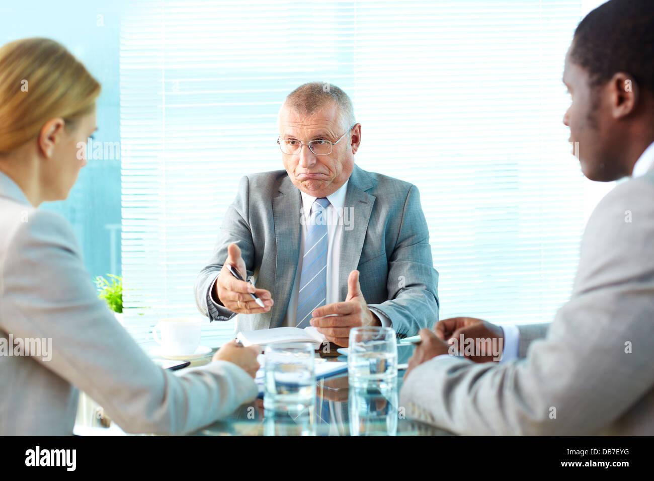 Portrait of serious boss talking to his employees Stock Photo - Alamy
