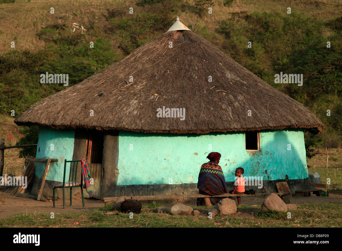 a woman and baby outside a traditional thatch and mud hut in the ...