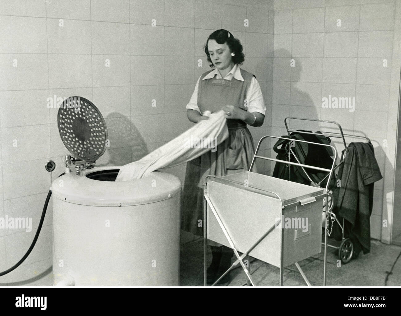 people, profession, woman working as laundress in the laundrette ...