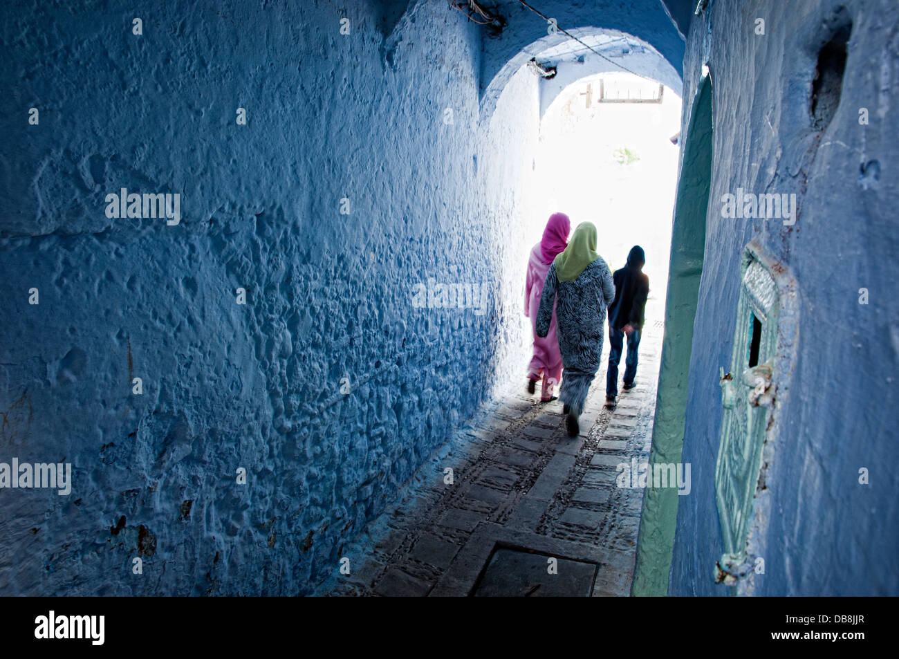People walking through an archway in the blue medina of Chefchaouen ...