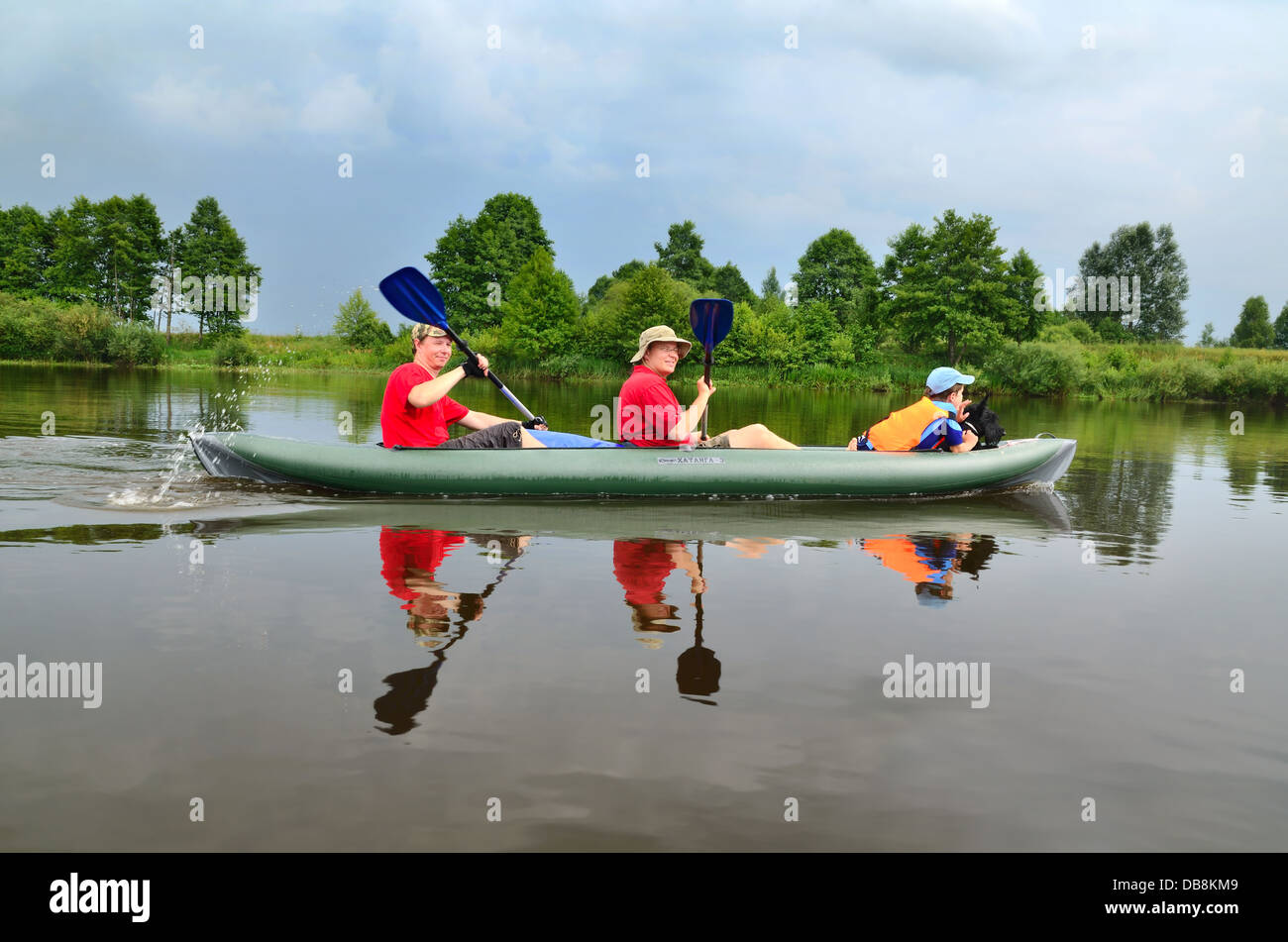 Three kayakers with dog in inflatable kayak enjoying paddling on the ...