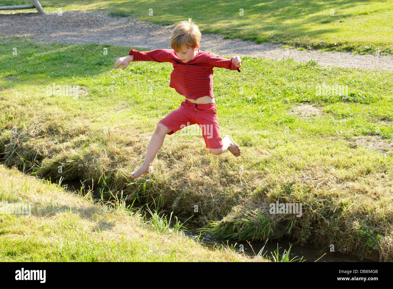 young boy jumping across a stream Stock Photo - Alamy