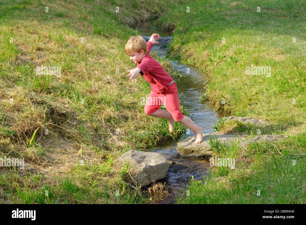 young boy jumping across a stream Stock Photo - Alamy