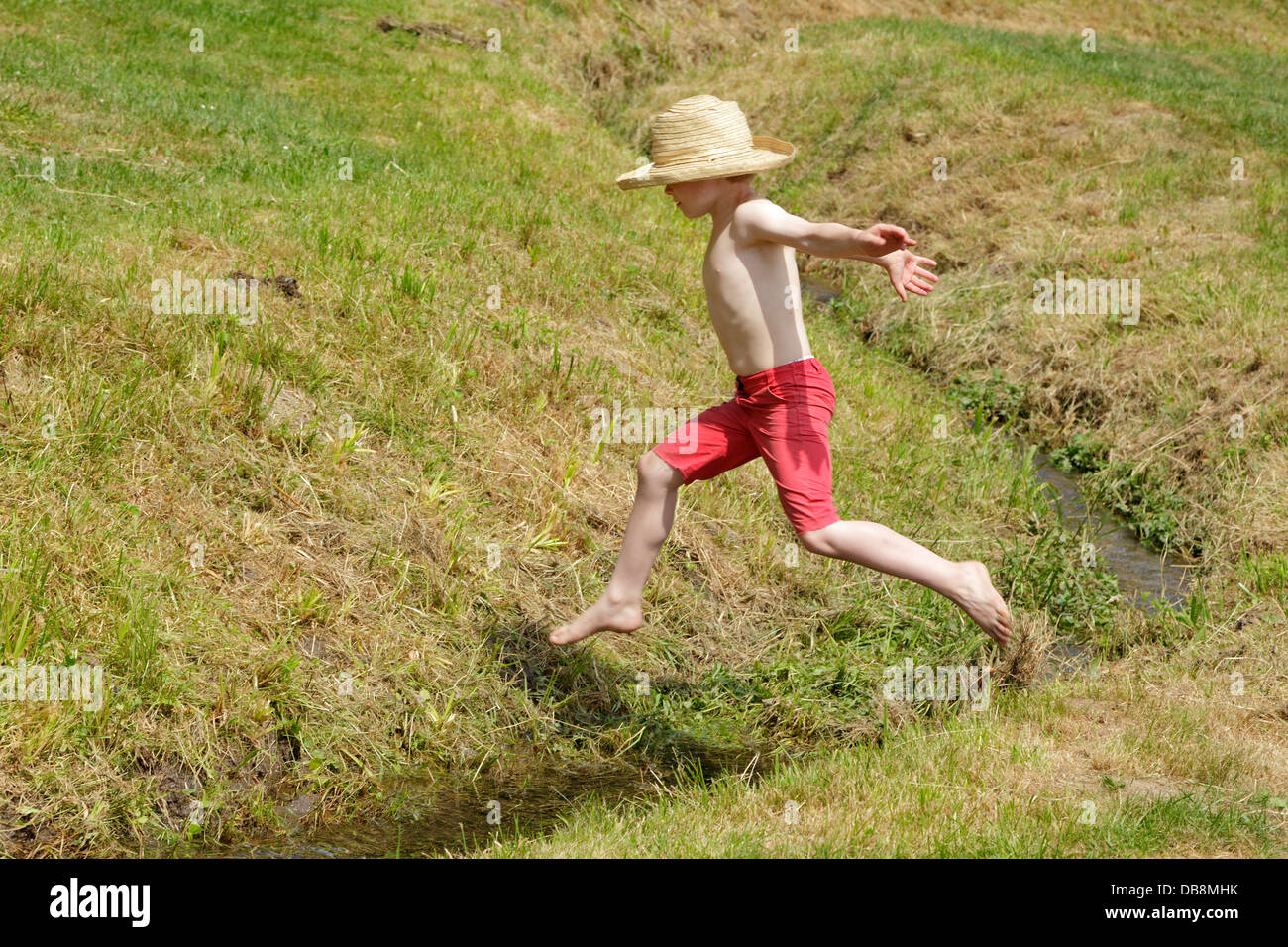 young boy jumping across a stream Stock Photo - Alamy
