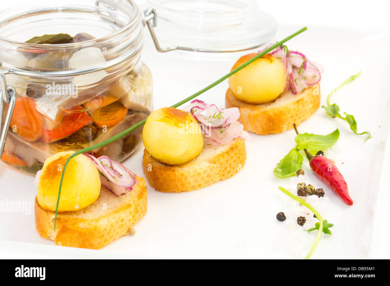 pickled herring in a glass jar with potato canapes Stock Photo - Alamy