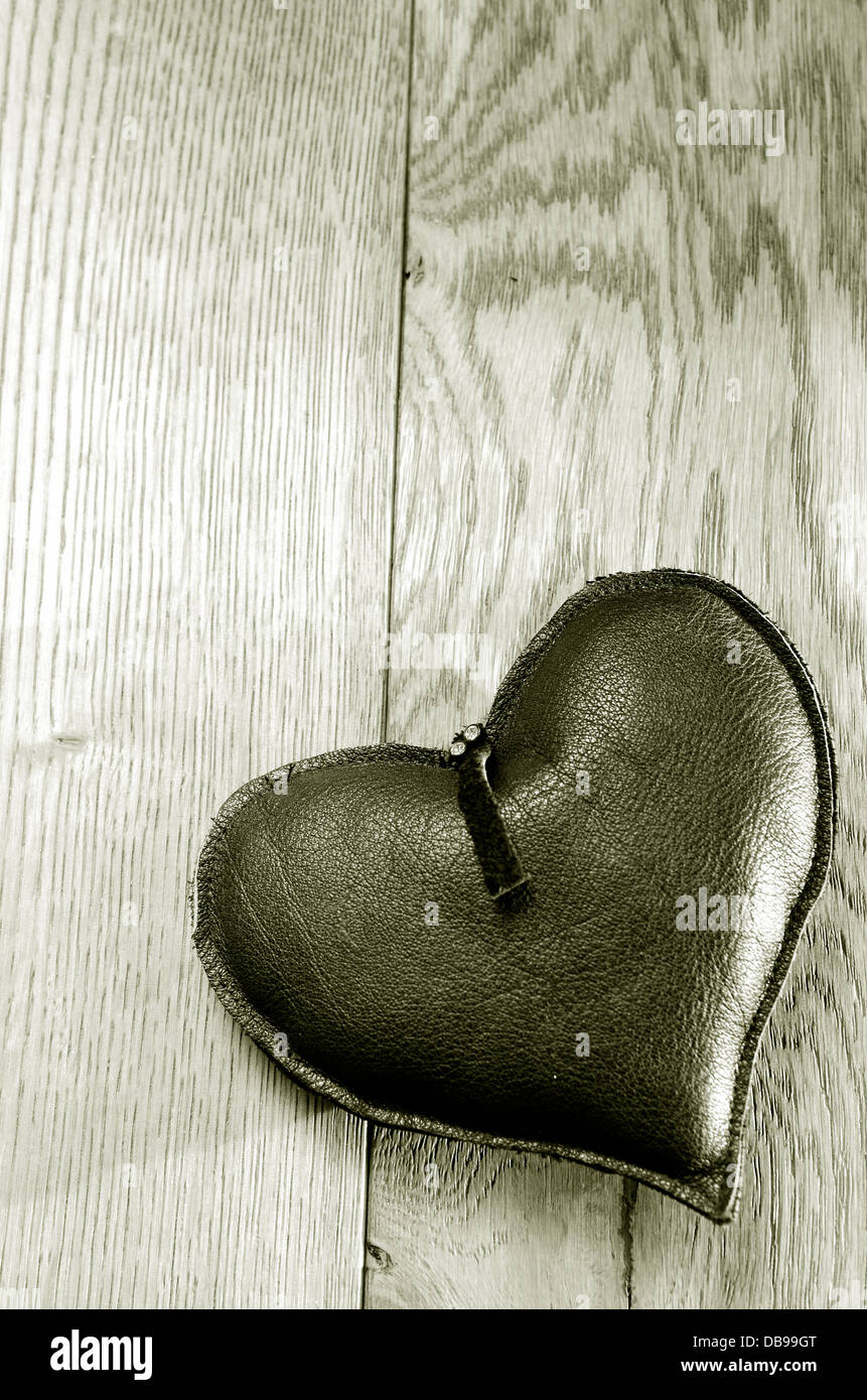 Black leather trimmed heart shape on a wooden background Stock Photo ...