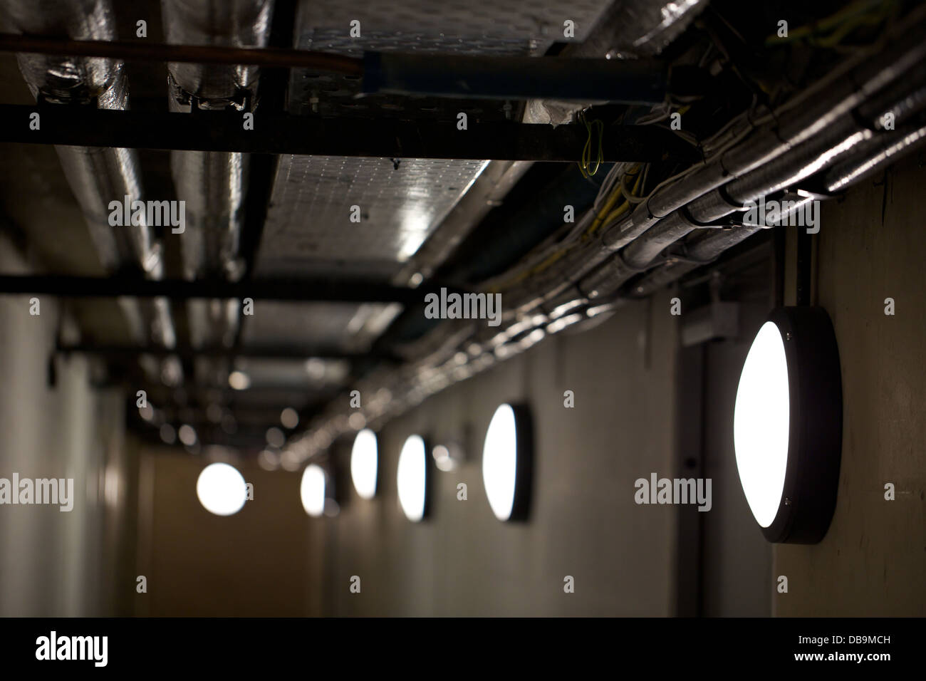 An underground basement passage way, dimly lit with pipes and services ...