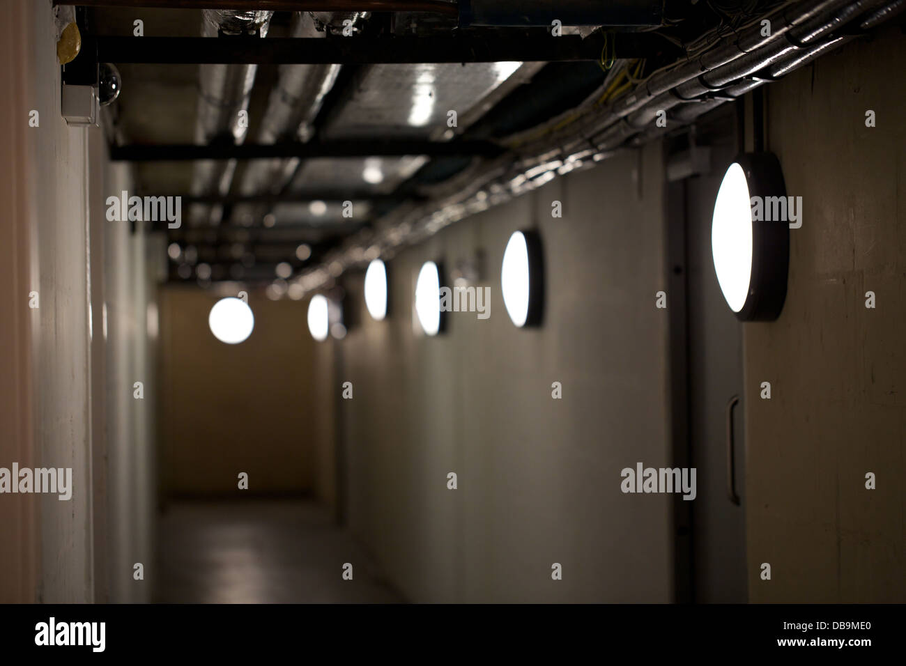 An underground basement passage way, dimly lit with pipes and services ...