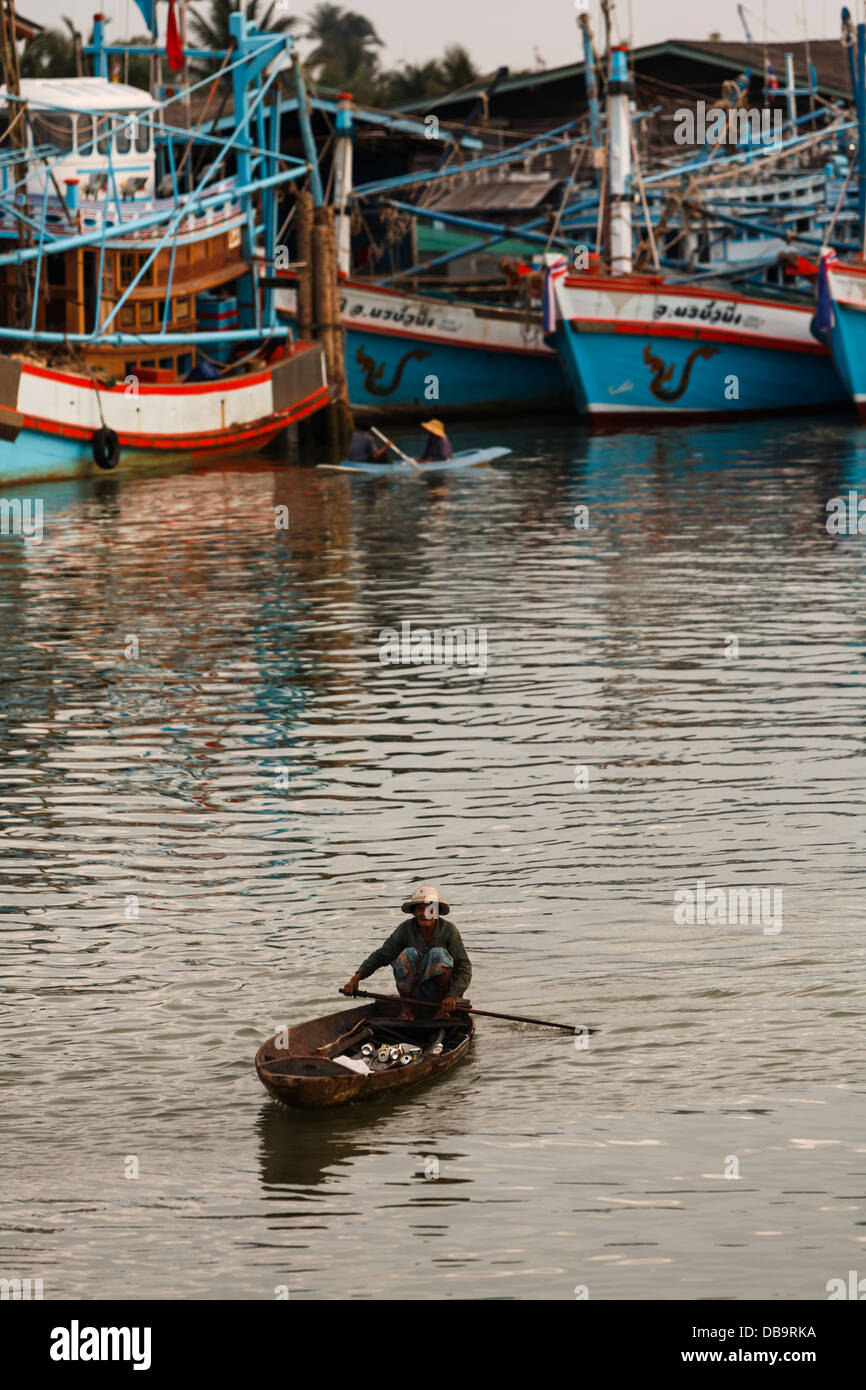 Two natives paddle small flat low narrow boats around the fishing ...
