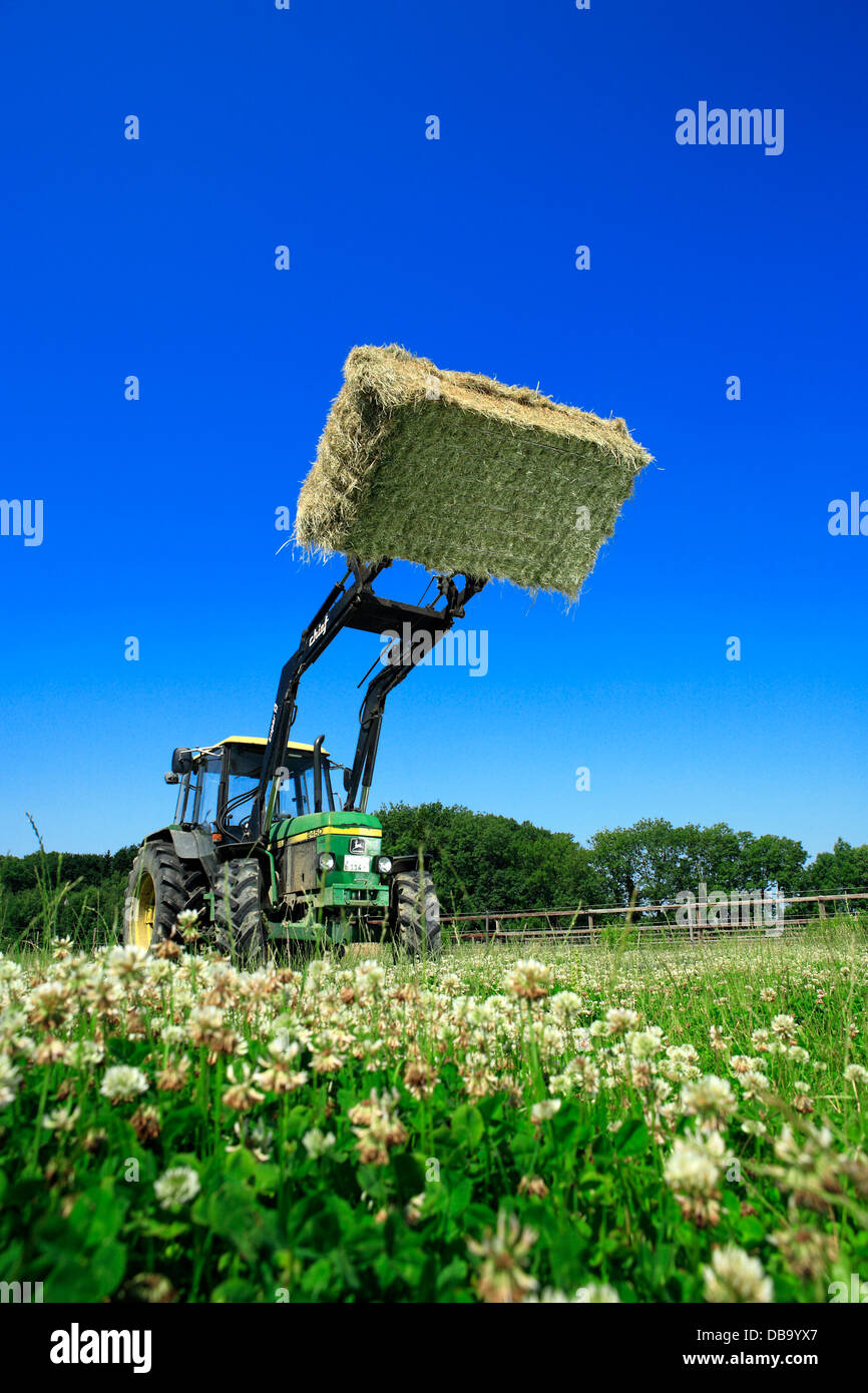 john deere tractor model 2450 lift bale hay on a farm's meadow. germany ...