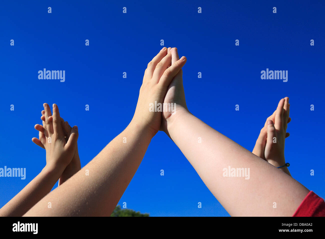 three teenager stretch their hands into the air and touching each ...