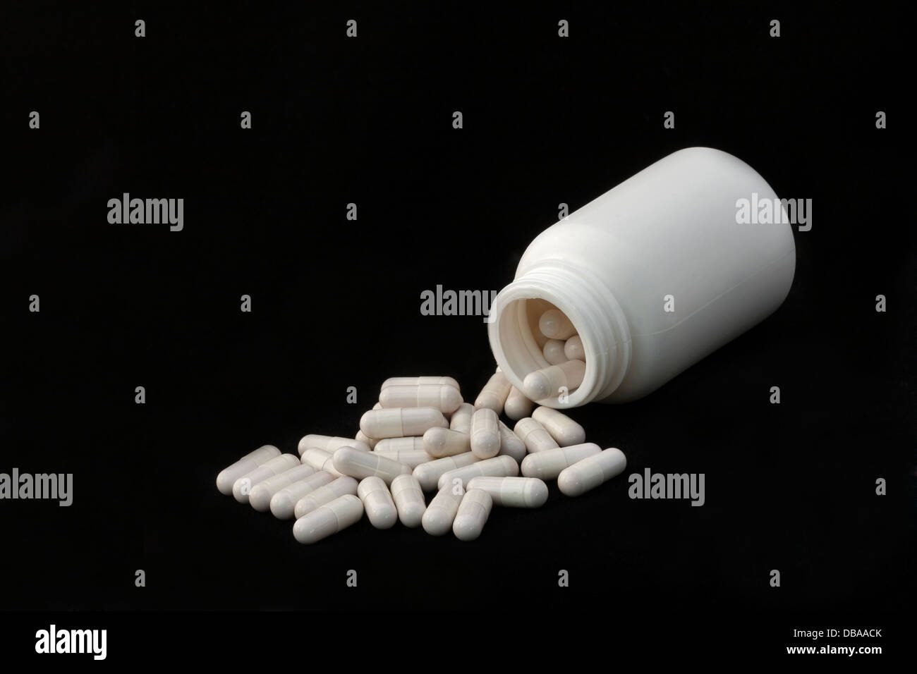 inverted bottle with white capsules closeup against black Stock Photo ...