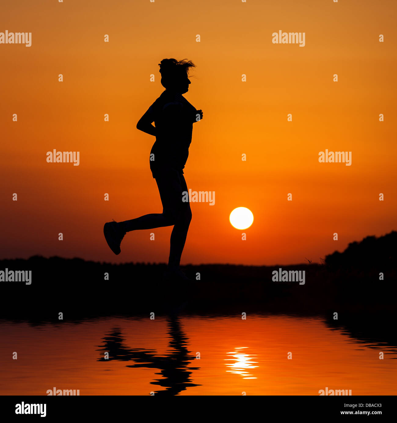 Silhouette woman running against orange sunset with reflection in water ...