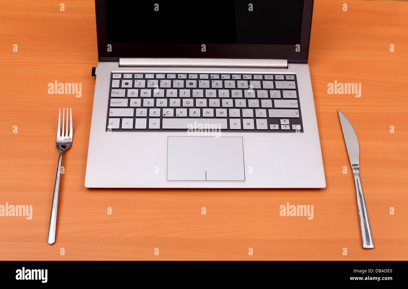 Laptop computer with fork and knife Stock Photo - Alamy
