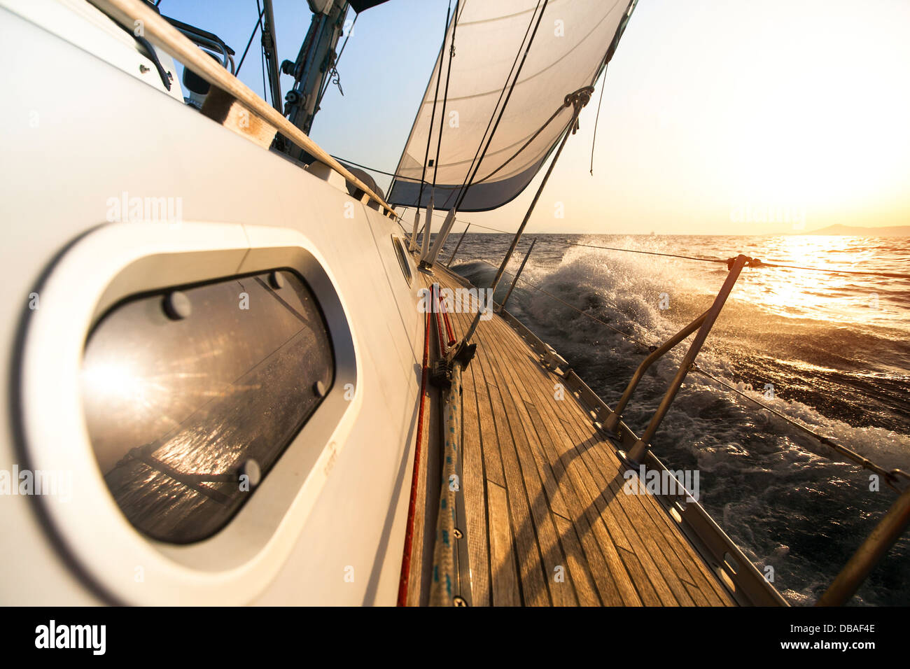 Yacht sailing towards the sunset Stock Photo - Alamy