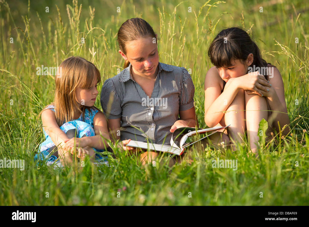 Children reading book in natural environment together Stock Photo - Alamy
