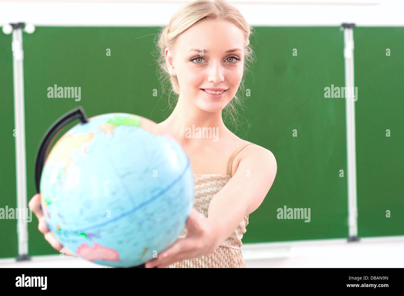 portrait of a young teacher holding a globe in the classroom Stock ...