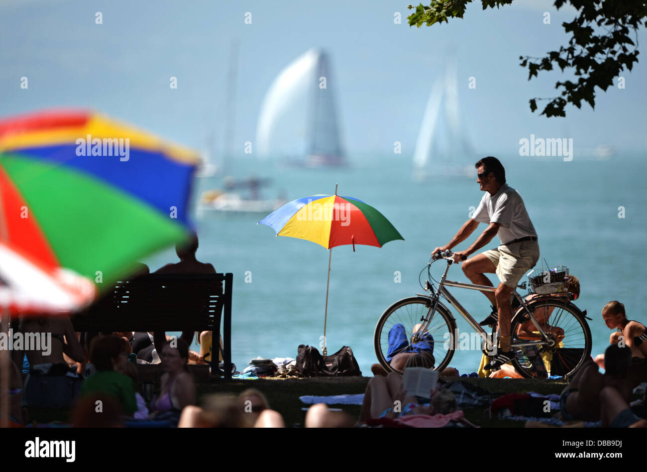 A man cycles along the banks of Lake Constance while people sit in the ...