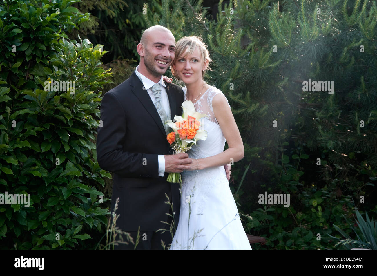 Bride and groom posing in the garden in the afternoon sun Stock Photo ...
