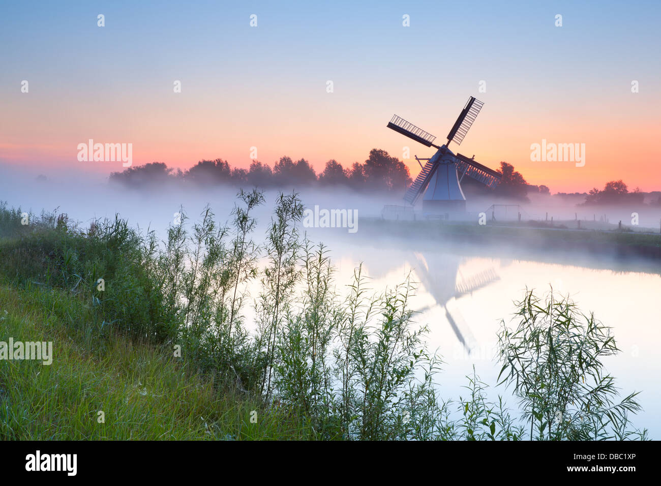 charming Dutch windmill by river at sunrise Stock Photo - Alamy