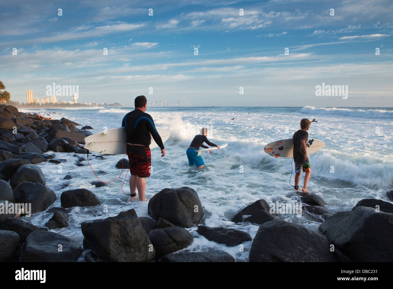 Surfers climbing over rocks to reach surf at Burleigh Heads. Gold Coast ...