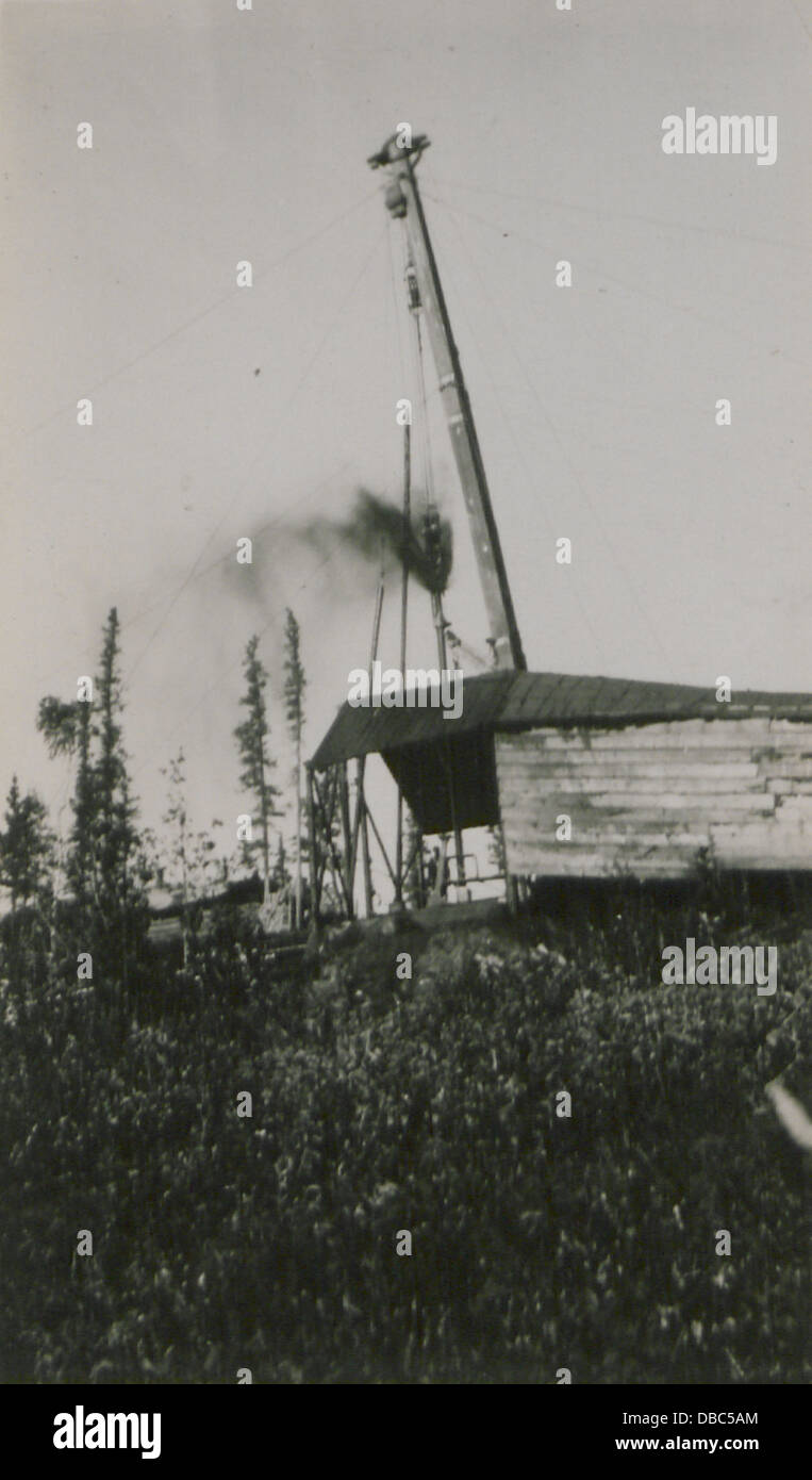 This photograph captures the first oil gusher at Fort Norman, marking a ...