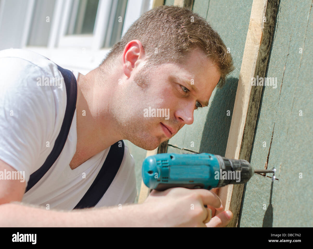 Young handsome handyman using screwdriver Stock Photo - Alamy